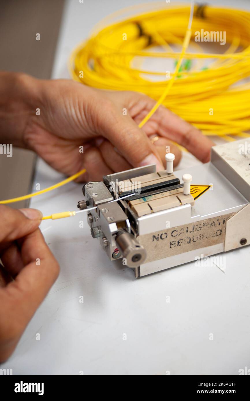 Technician cleaving an optical fiber, a crucial process for a good ...