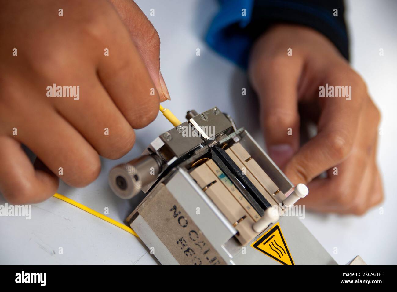 Technician cleaving an optical fiber, a crucial process for a good ...