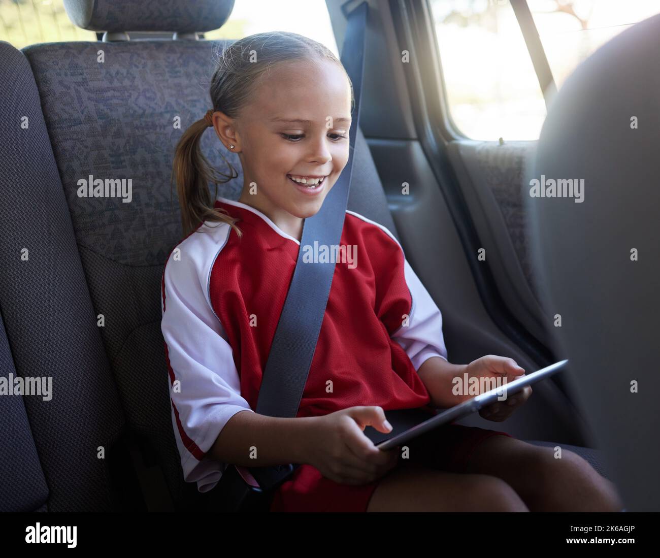 Happy, girl child and with tablet in car smile, browse online and use ...