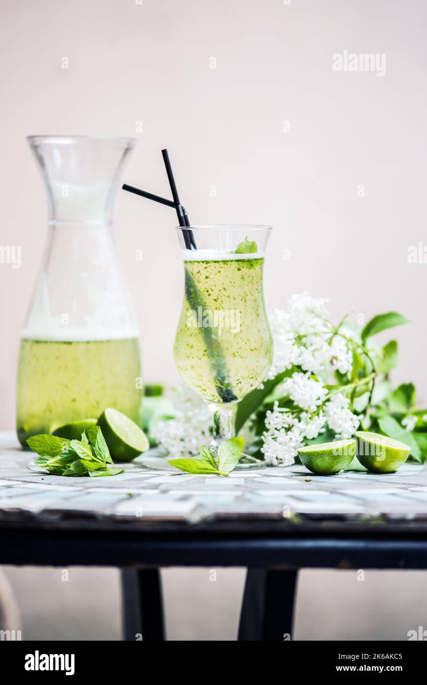 A closeup of decanter and glass with lime cocktail surrounded by ...