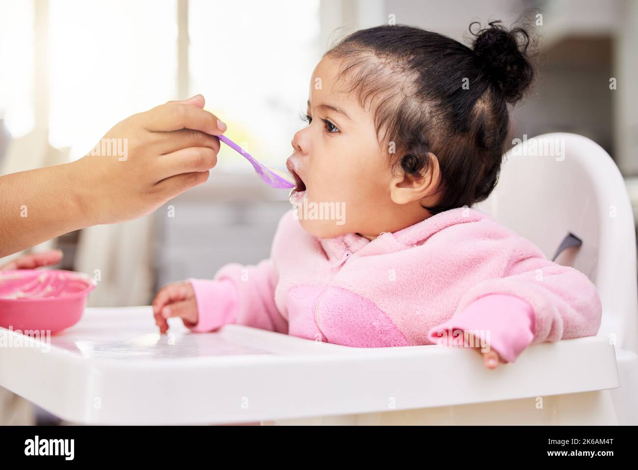 Mom feeding her baby girl with a spoon. Adorable baby girl opening her ...