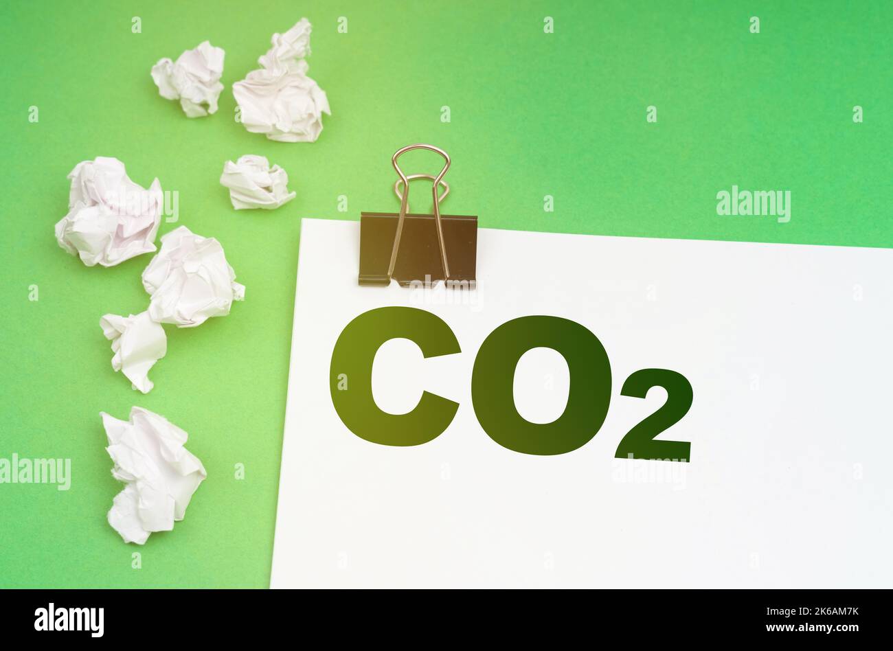 Ecology concept. On a green background, crumpled paper and a sheet with ...