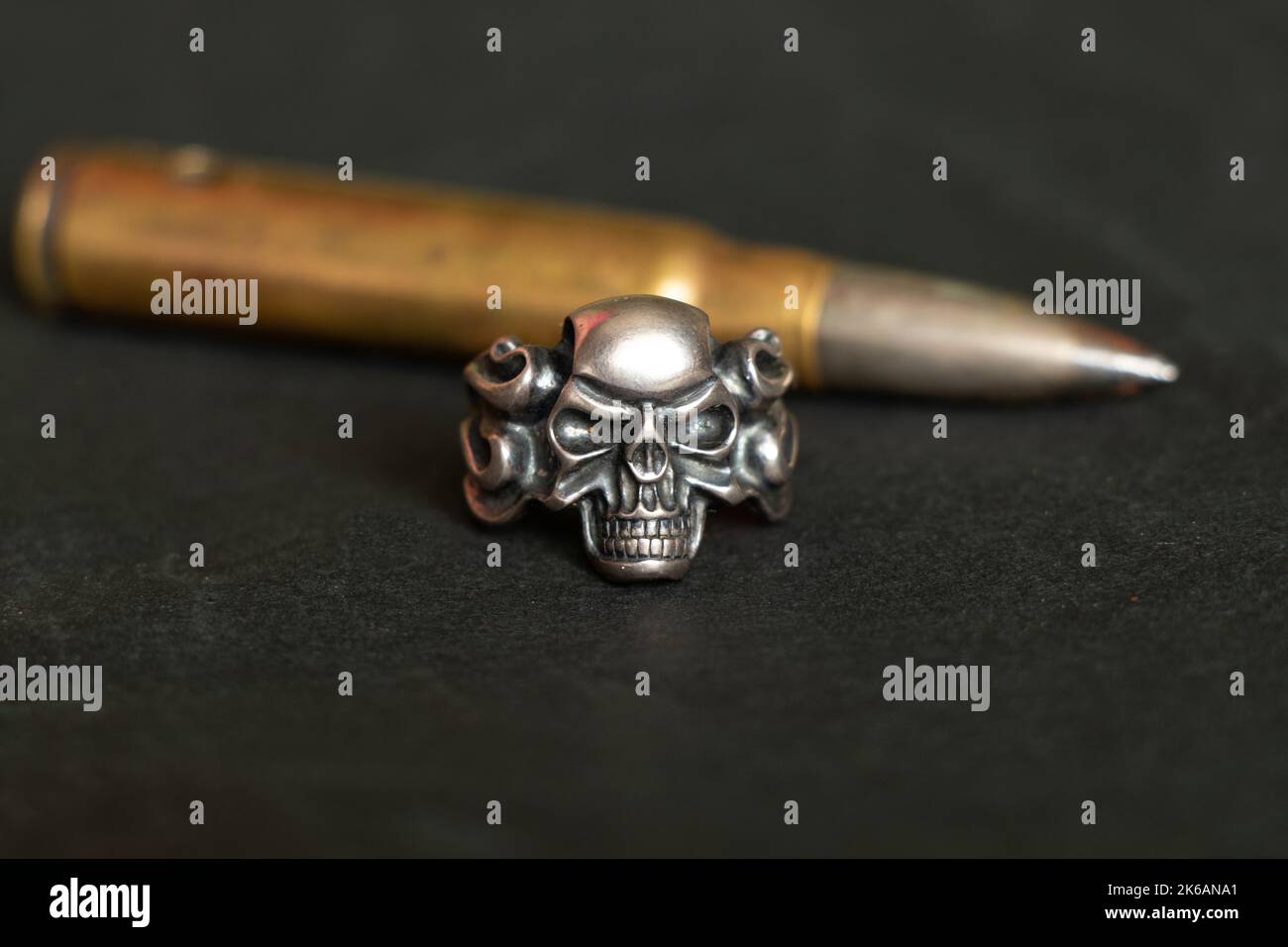 Silver ring with a skull and a bullet on a dark background, death and ...