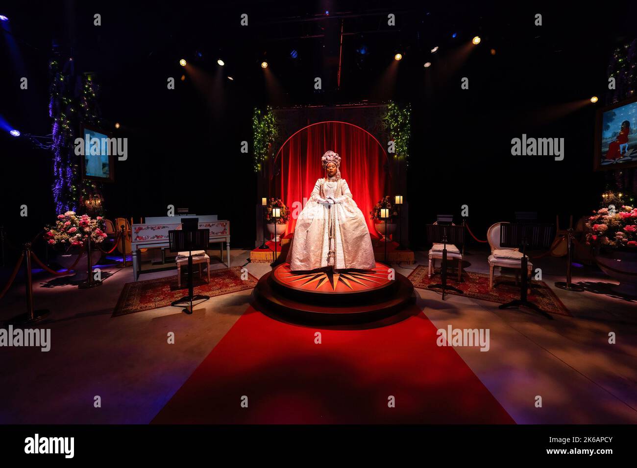 A woman dressed as a queen poses on a throne. The "Queen's Ball ...