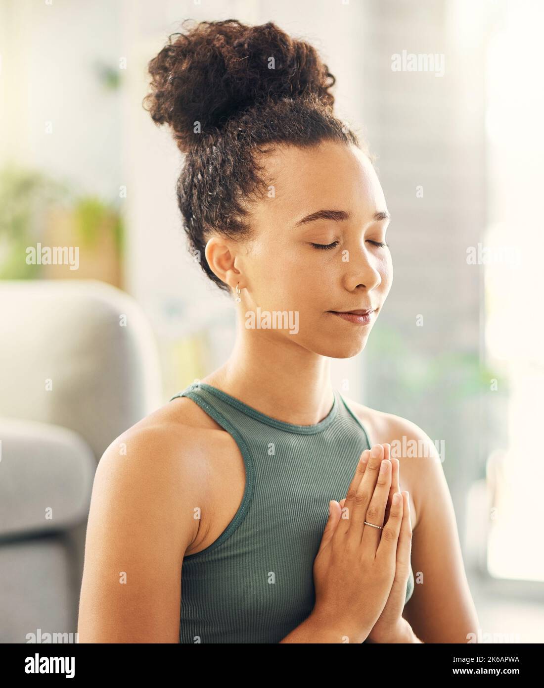 Think positive thoughts. a young woman meditating in her living room ...