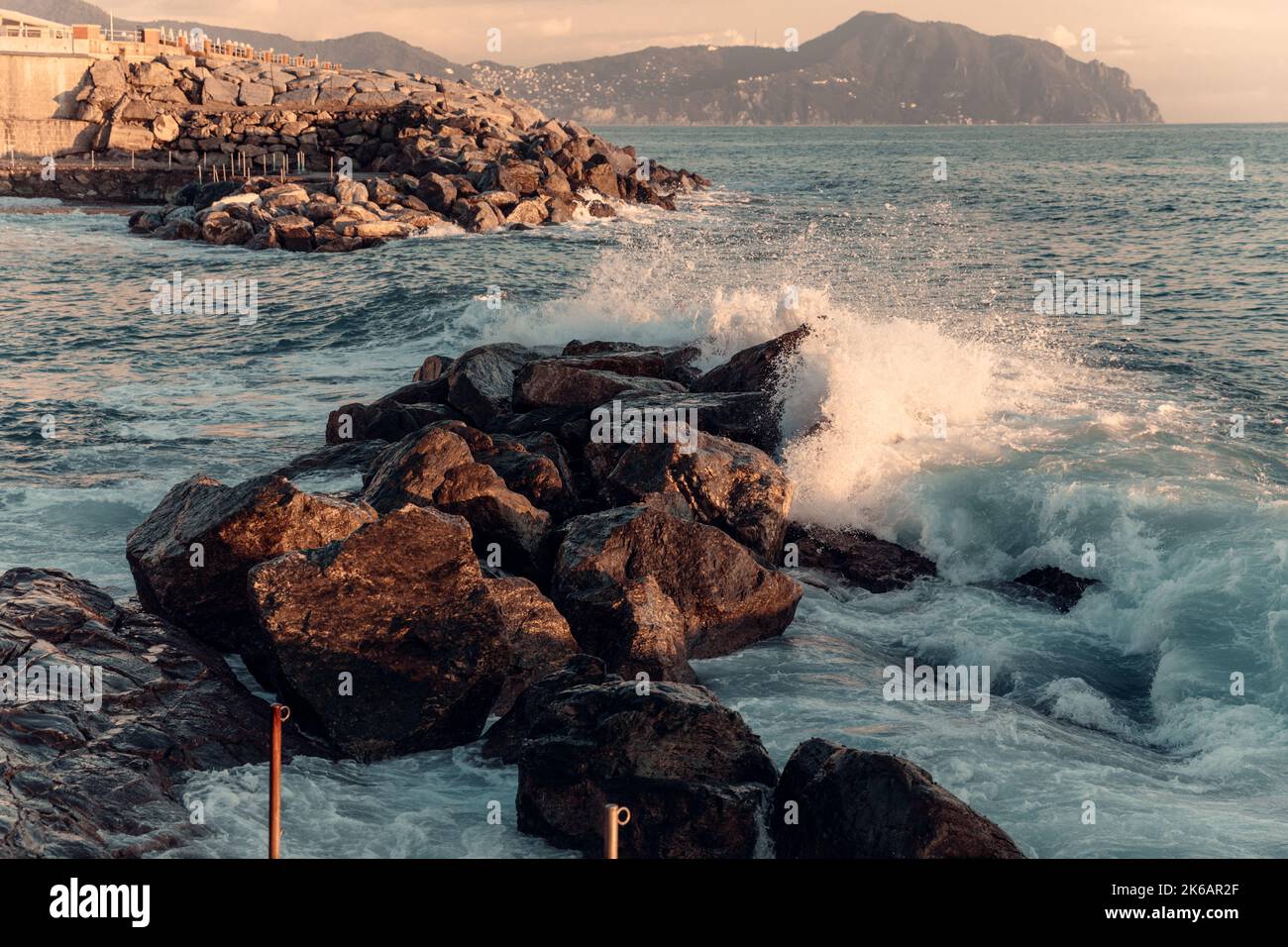 The sea waves splashing over rocks on the beach with mountains in the ...
