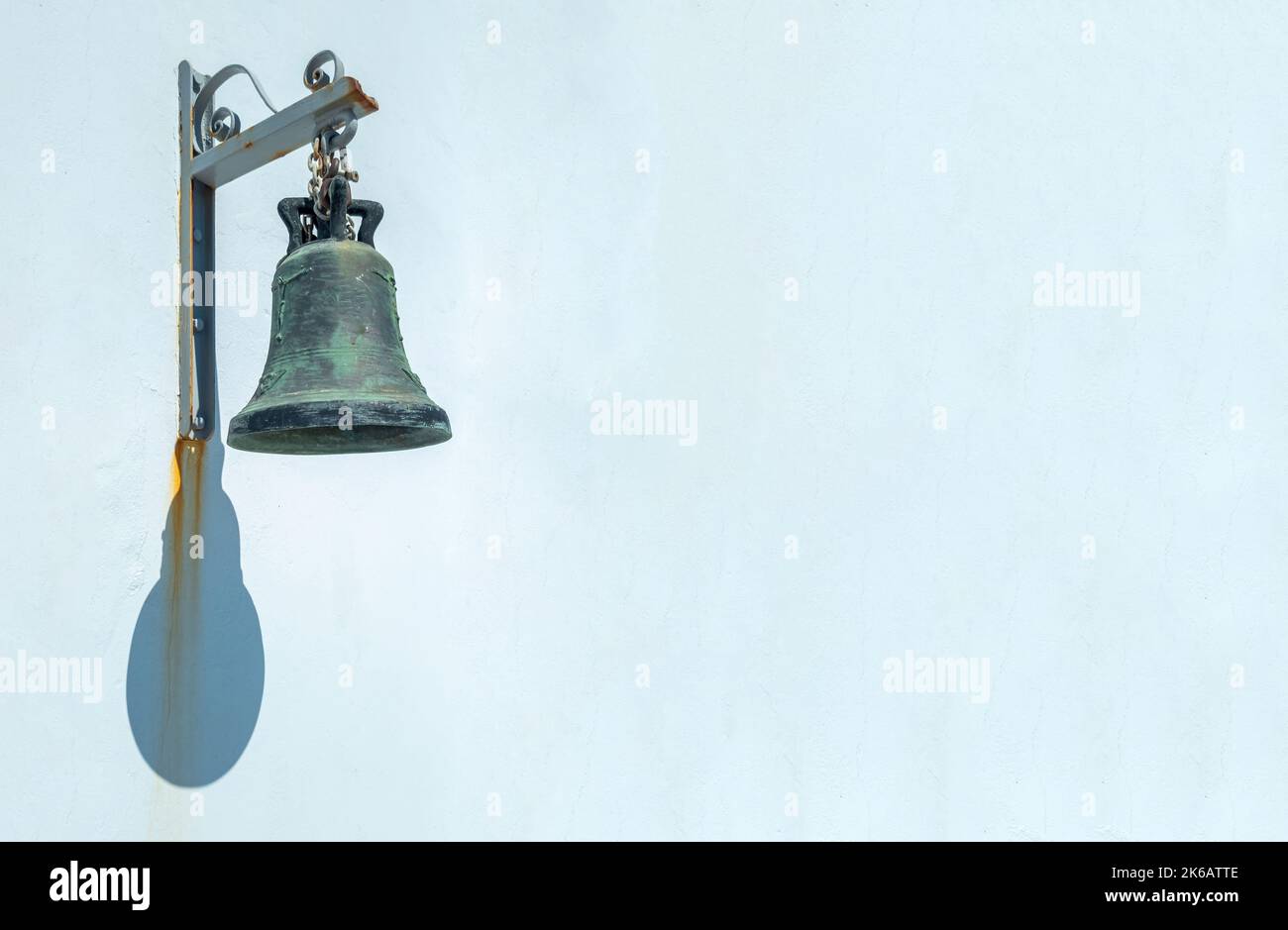 Vintage bell hanging from metallic base on light blue empty wall ...