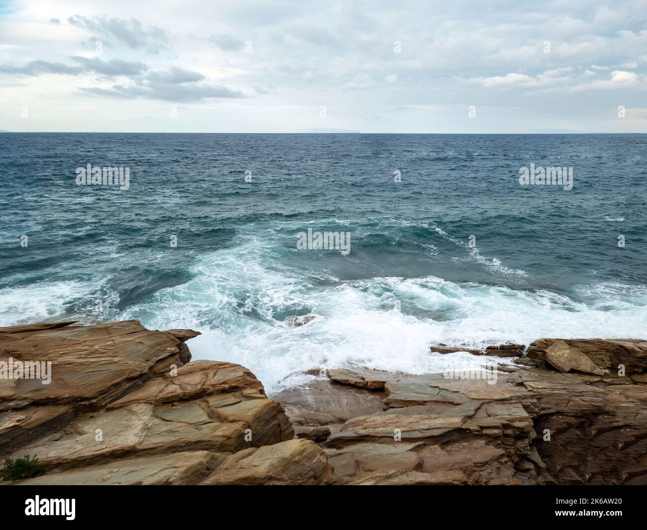 Sea ripple water white foam on wet rock surface, cloudy sky background ...