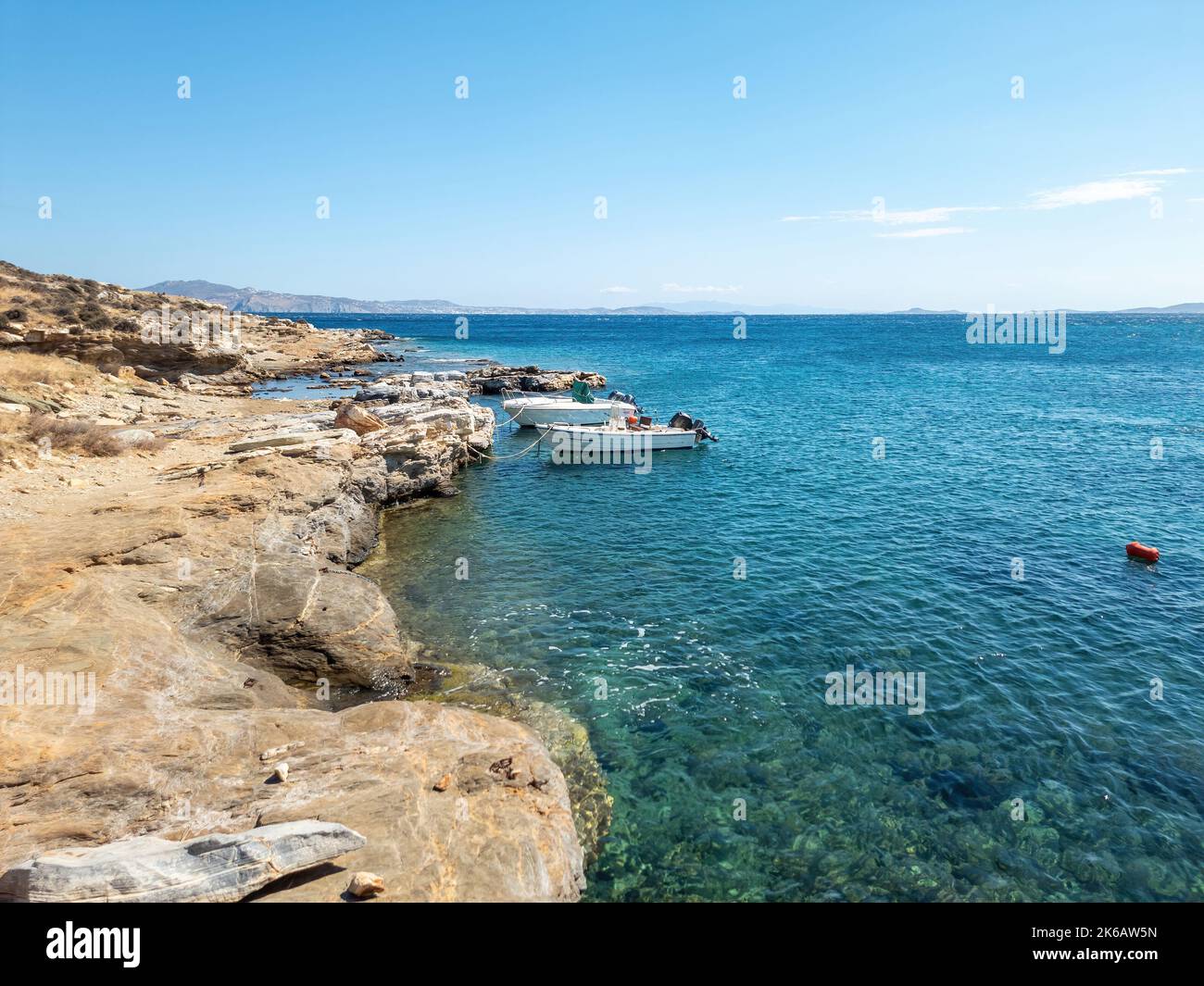 Greece Tinos island, Cyclades. Moored yachts at seaside rocky land in ...
