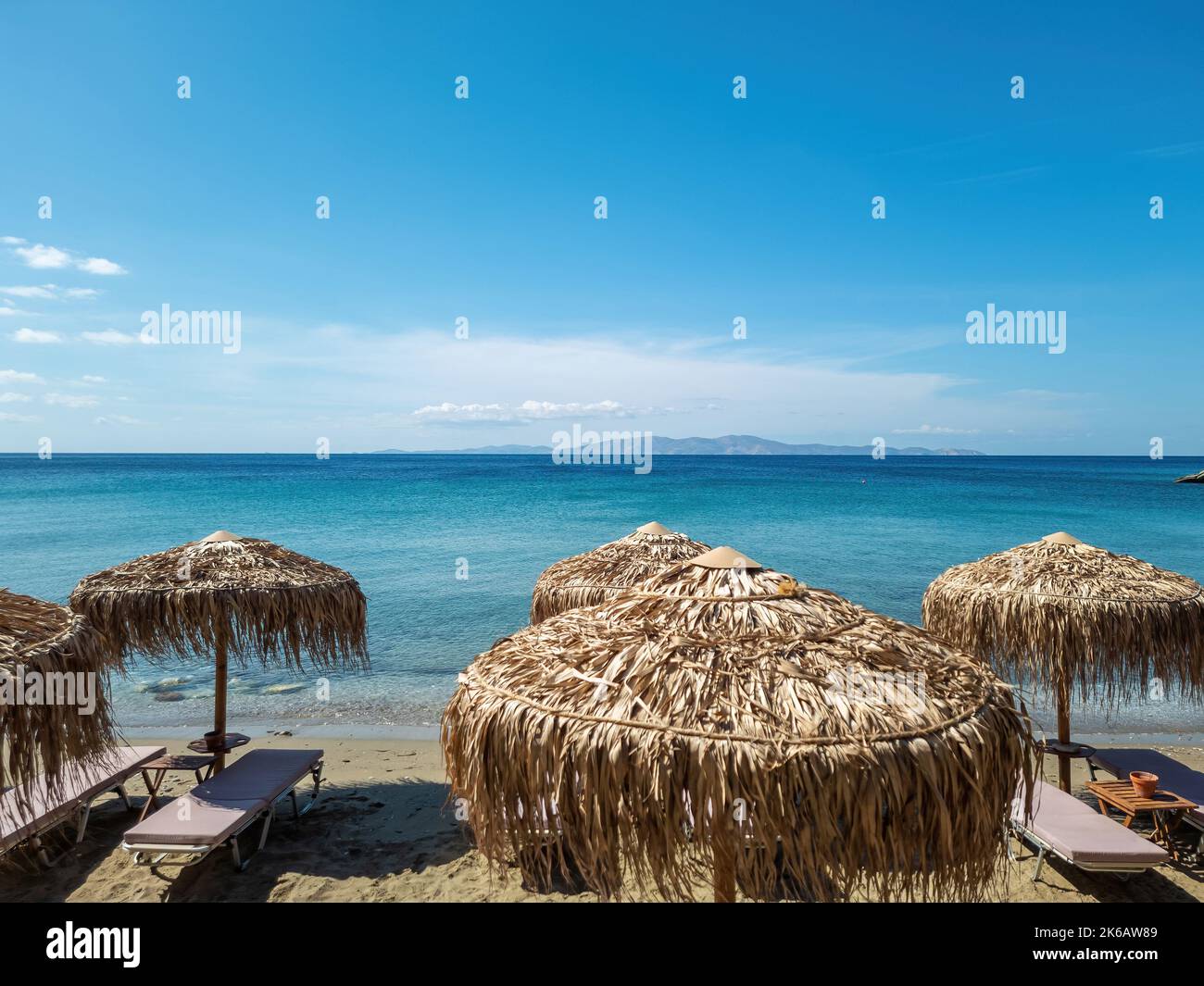 Greece. Straw umbrellas empty sun loungers under Greek summer sun ...