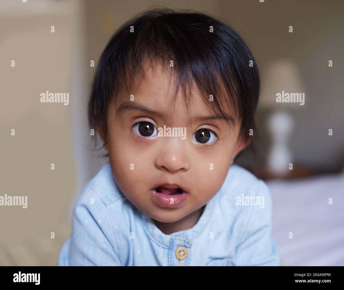 Face, down syndrome baby and bedroom portrait in home alone, looking ...