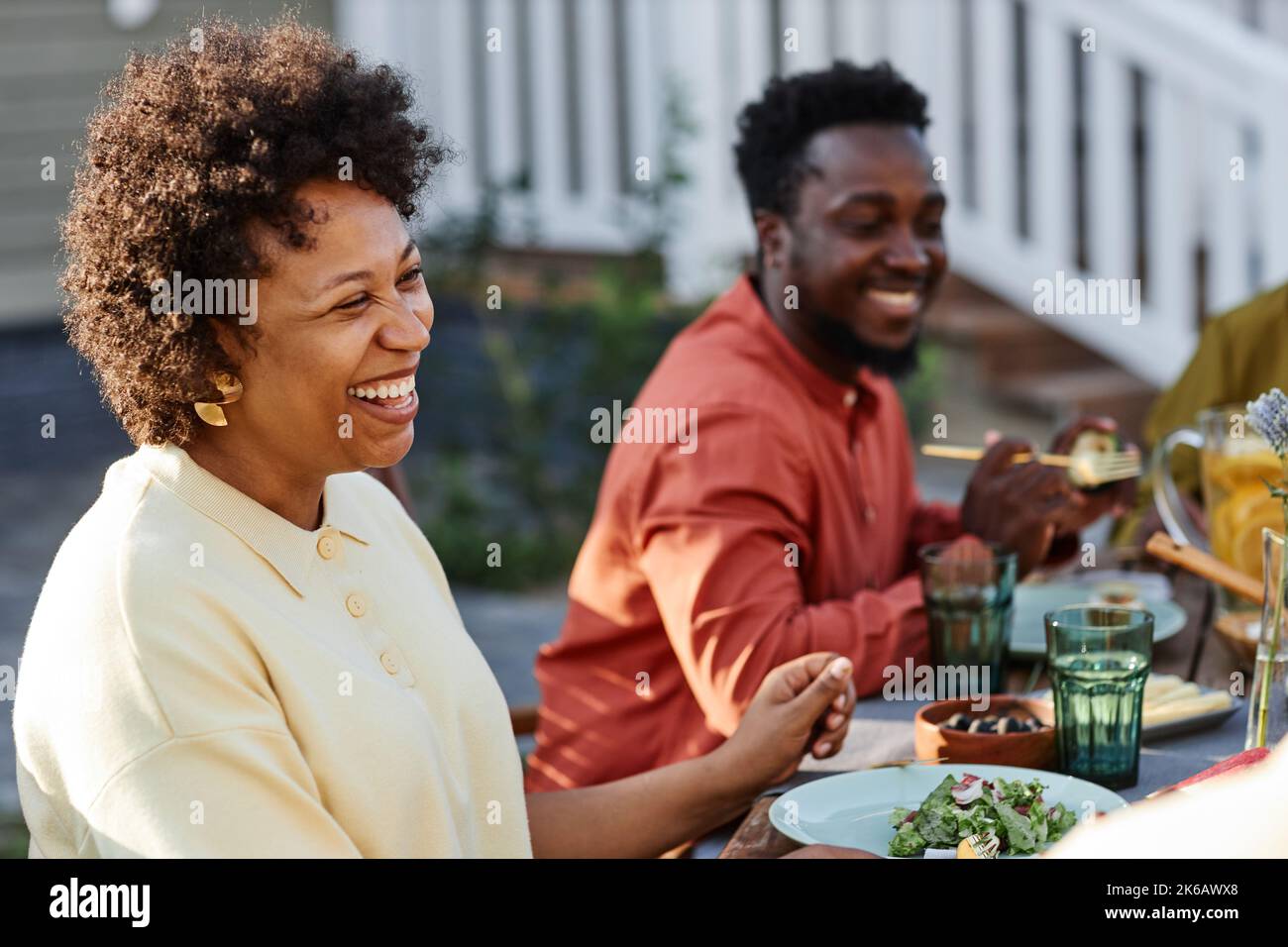 Portrait of happy African American family chatting at dinner table during Summer party outdoors ...