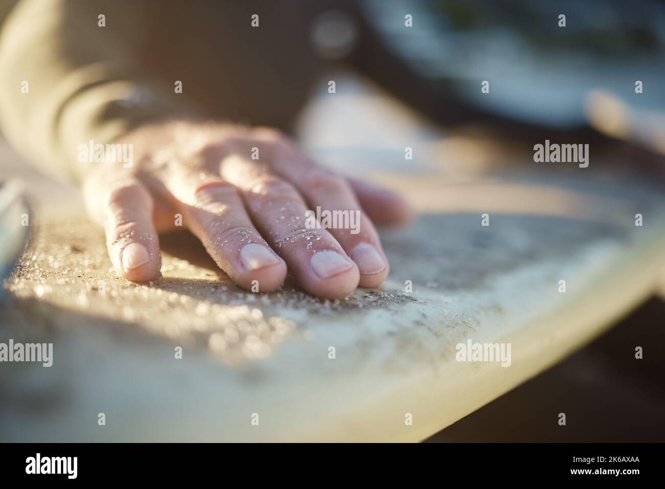 Hand, surfboard and sports with a man surfer cleaning sand from his ...