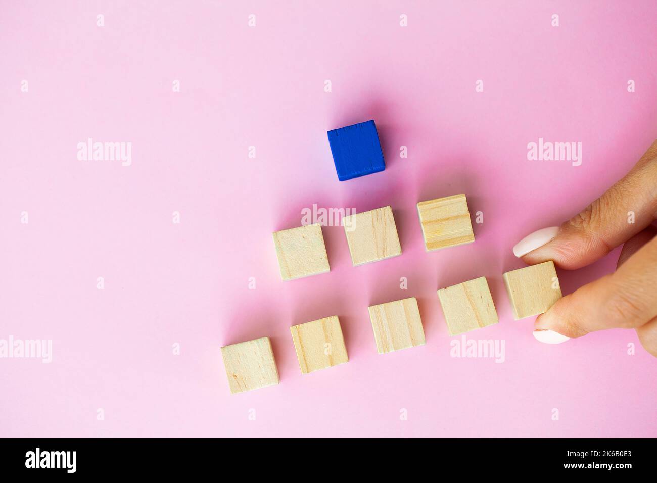 Wooden blocks with a human hand placing one cube at the top on pink ...