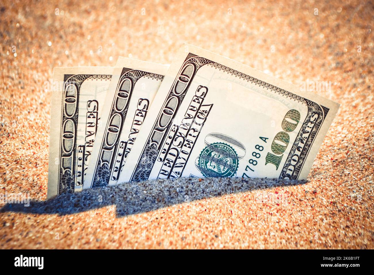 Money dolars half covered with sand lie on beach close-up. Money grows ...