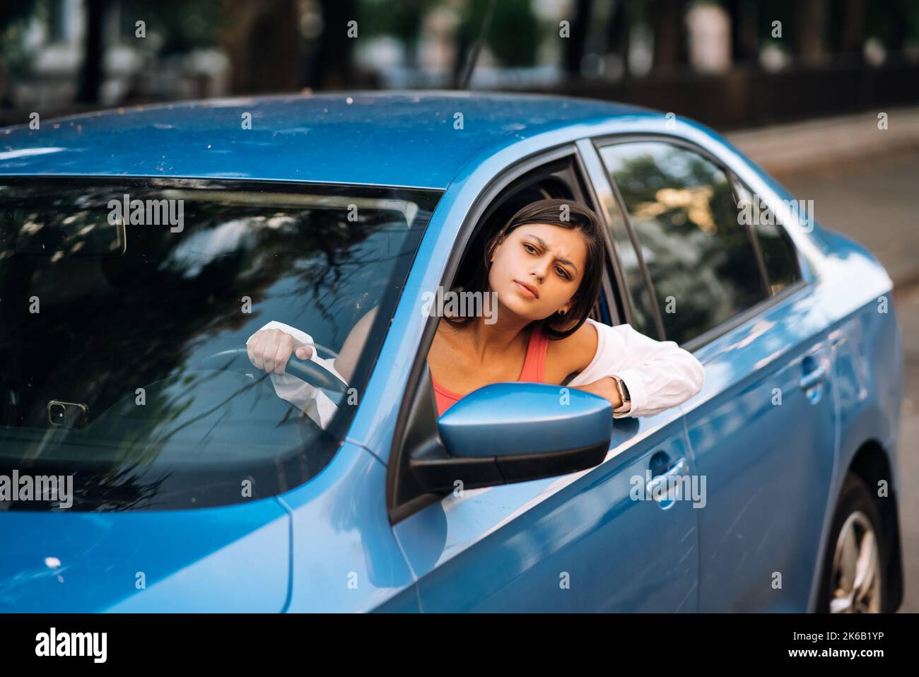 A young angry woman peeks out of the car window Stock Photo - Alamy