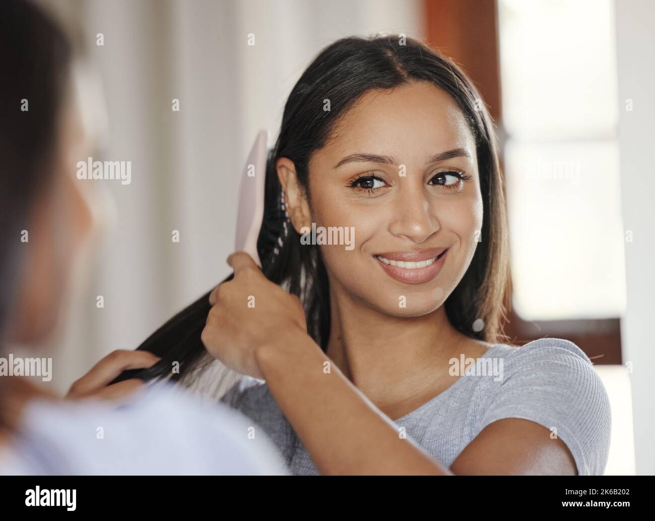 Brushing my way to silky soft hair. a young woman brushing her hair at ...
