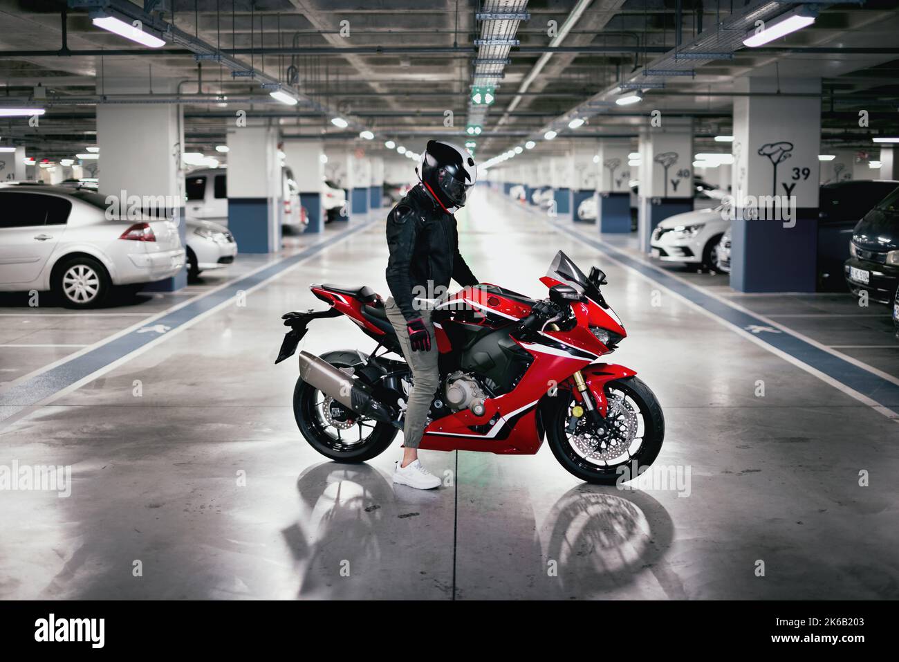 Side view of race motorcycle rider with a helmet in a car parking lot ...