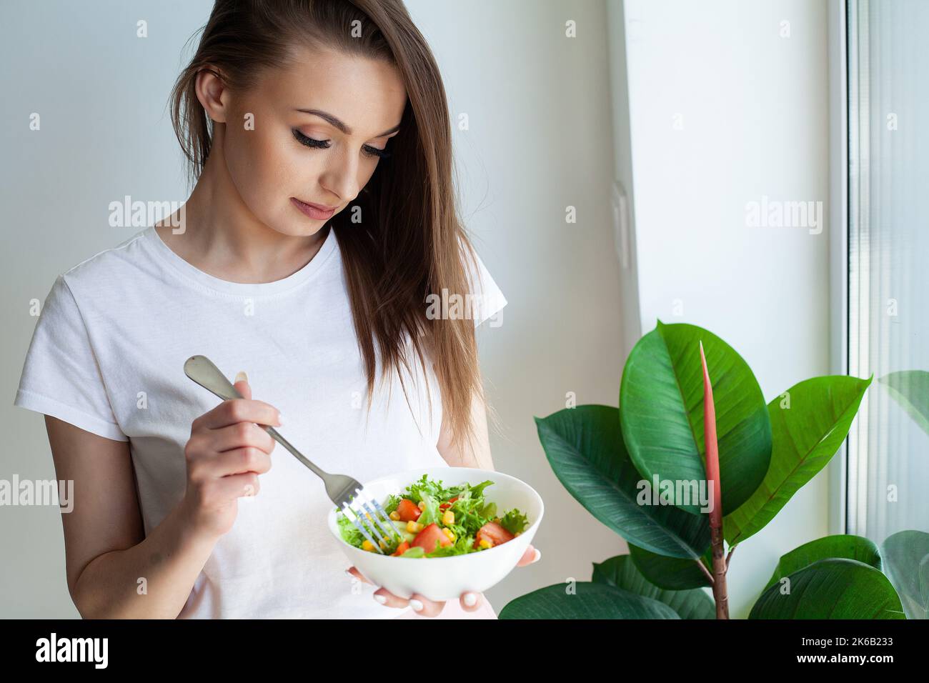 Young woman eating healthy food sitting in the light interior Stock ...