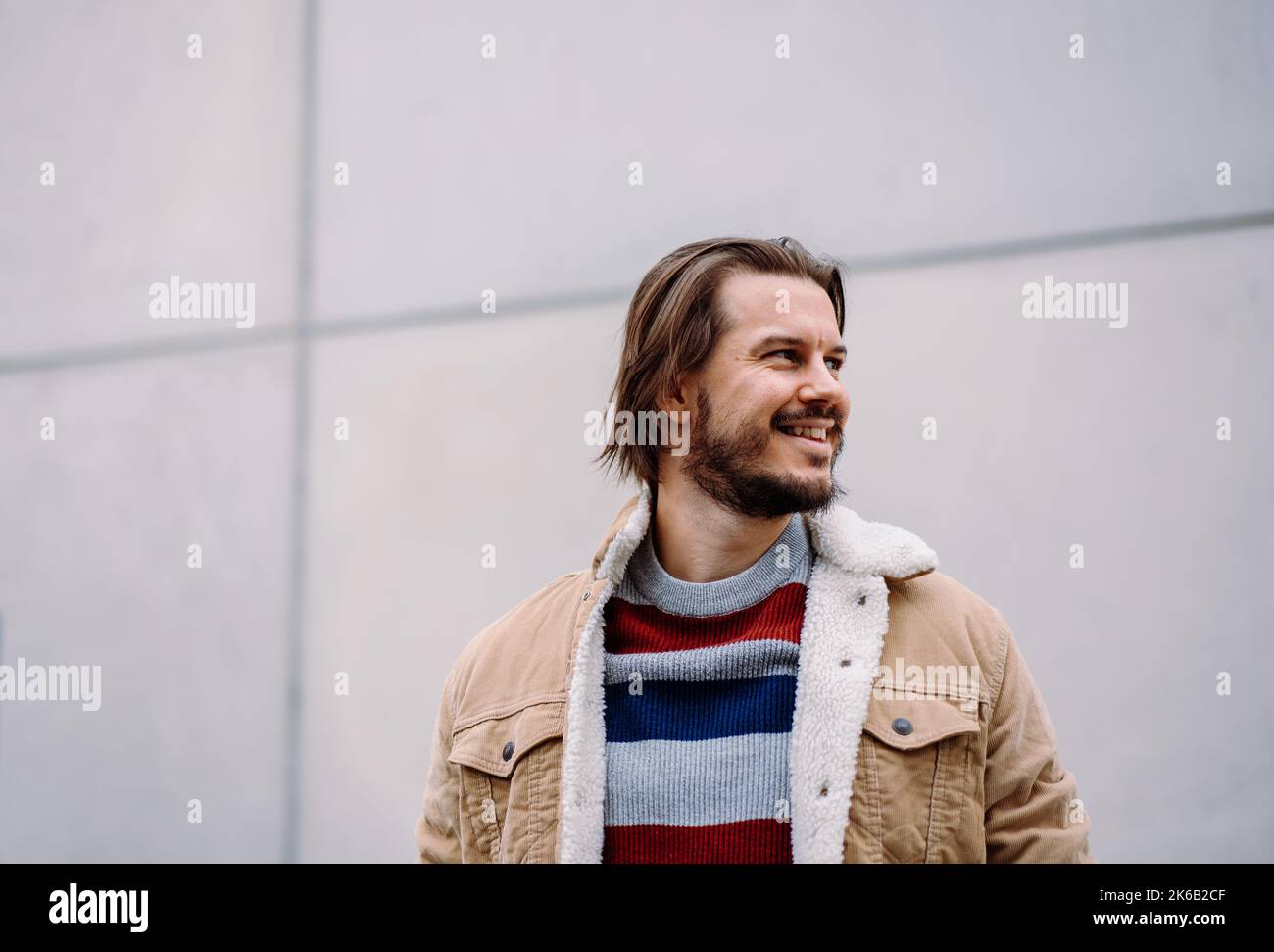 Smiling male model looking at the distance while posing over the blank ...