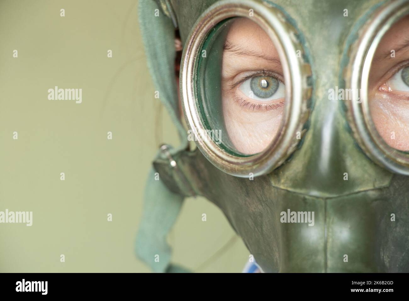 The face of a girl in a Soviet green gas mask on a green background ...