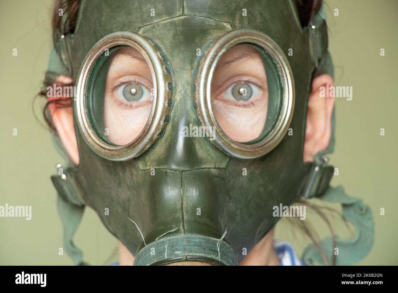 The face of a girl in a Soviet green gas mask on a green background ...