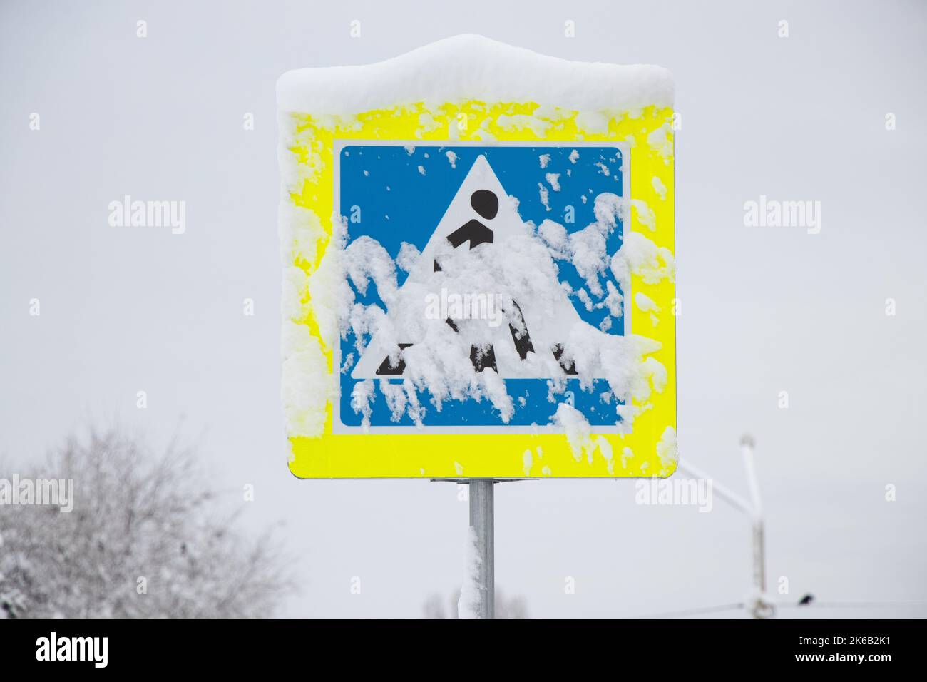 A sign of a pedestrian crossing in winter in the snow in the city drove ...