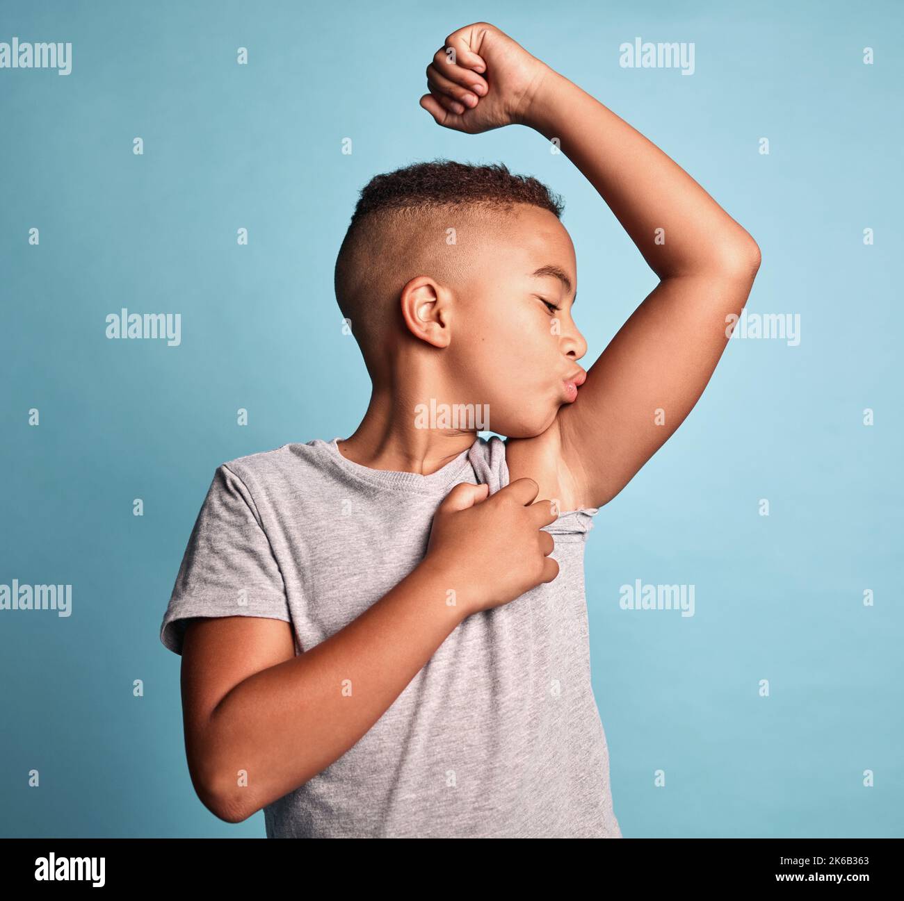 Children, bicep and kiss with a boy bodybuilder in studio on a blue ...