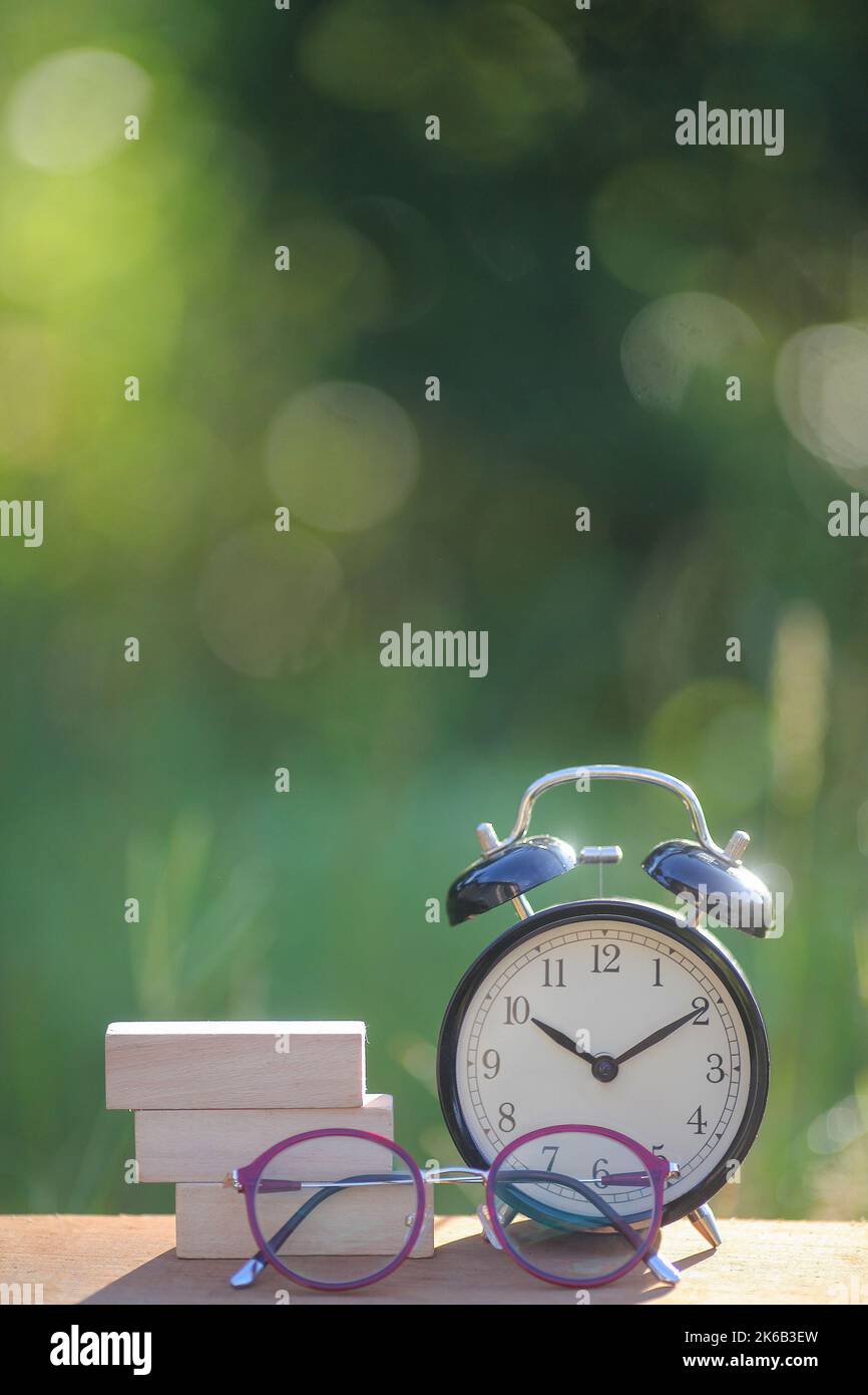 Black alarm clock stacked on wooden bar with shallow DOF green ...