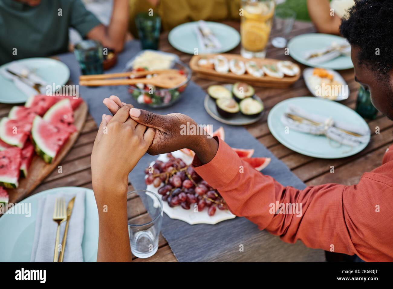 Close up of African American family saying grace at table outdoors and ...