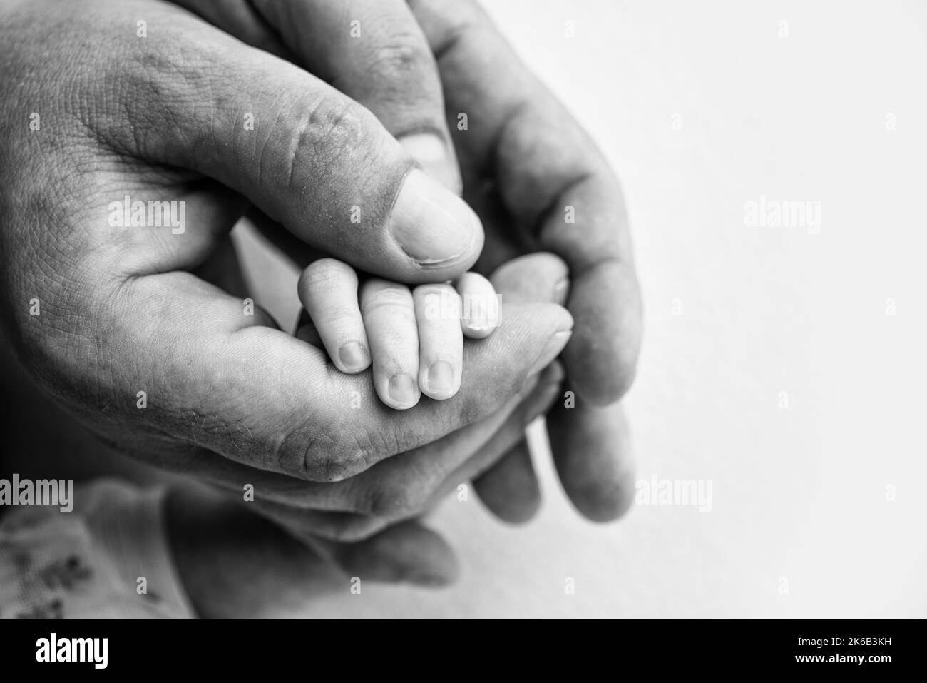 The hand of sleeping newborn in the hand of parents, mother and father ...