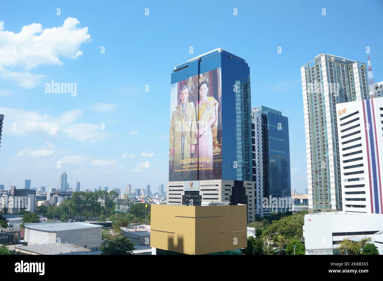 Skyscraper with big banner of Thai royal couple in Bangkok with bright ...