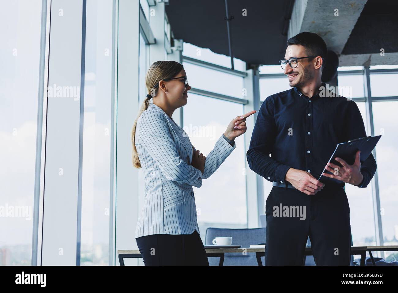 Positive businesswoman standing with Caucasian male colleague talking ...