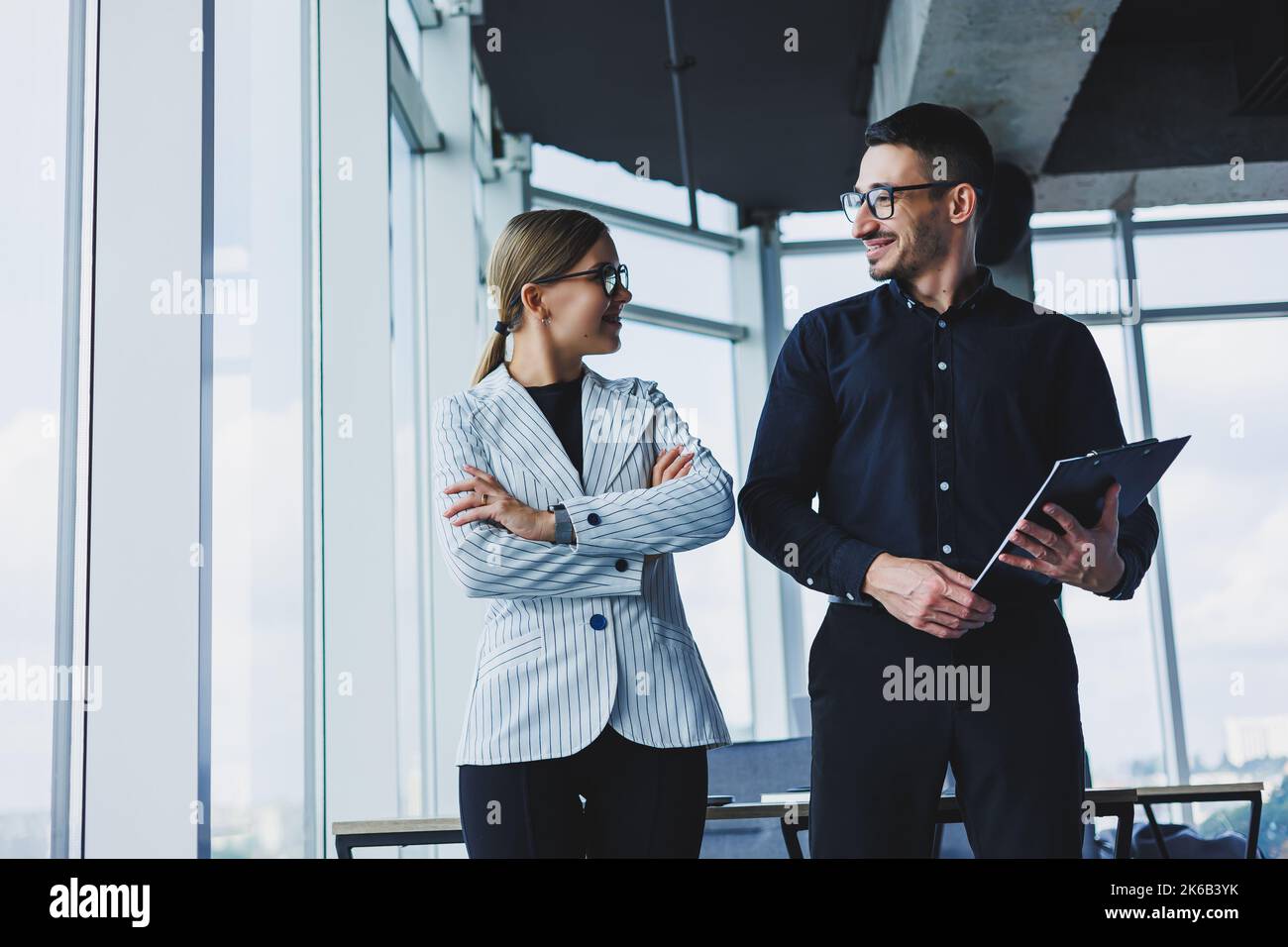 Positive businesswoman standing with Caucasian male colleague talking ...