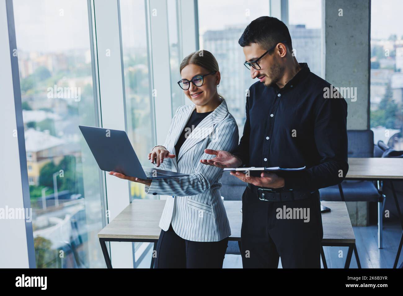 Beautiful businesswoman standing with Caucasian male colleague watching ...