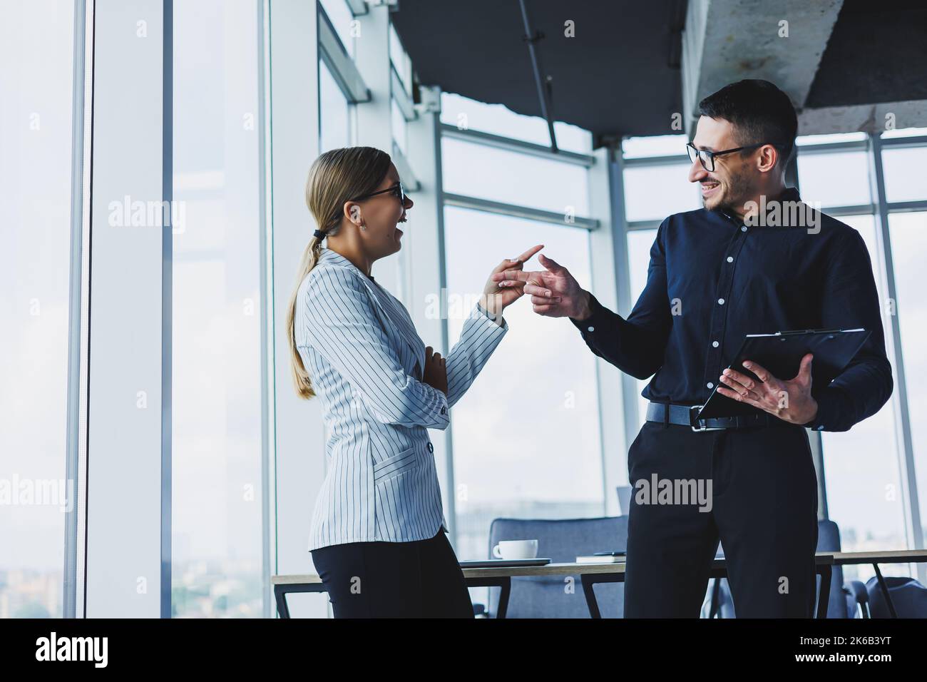 Positive businesswoman standing with Caucasian male colleague talking ...