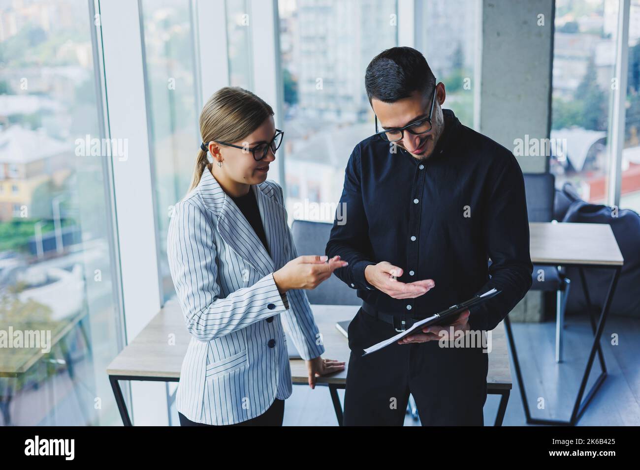 Positive businesswoman standing with Caucasian male colleague talking ...