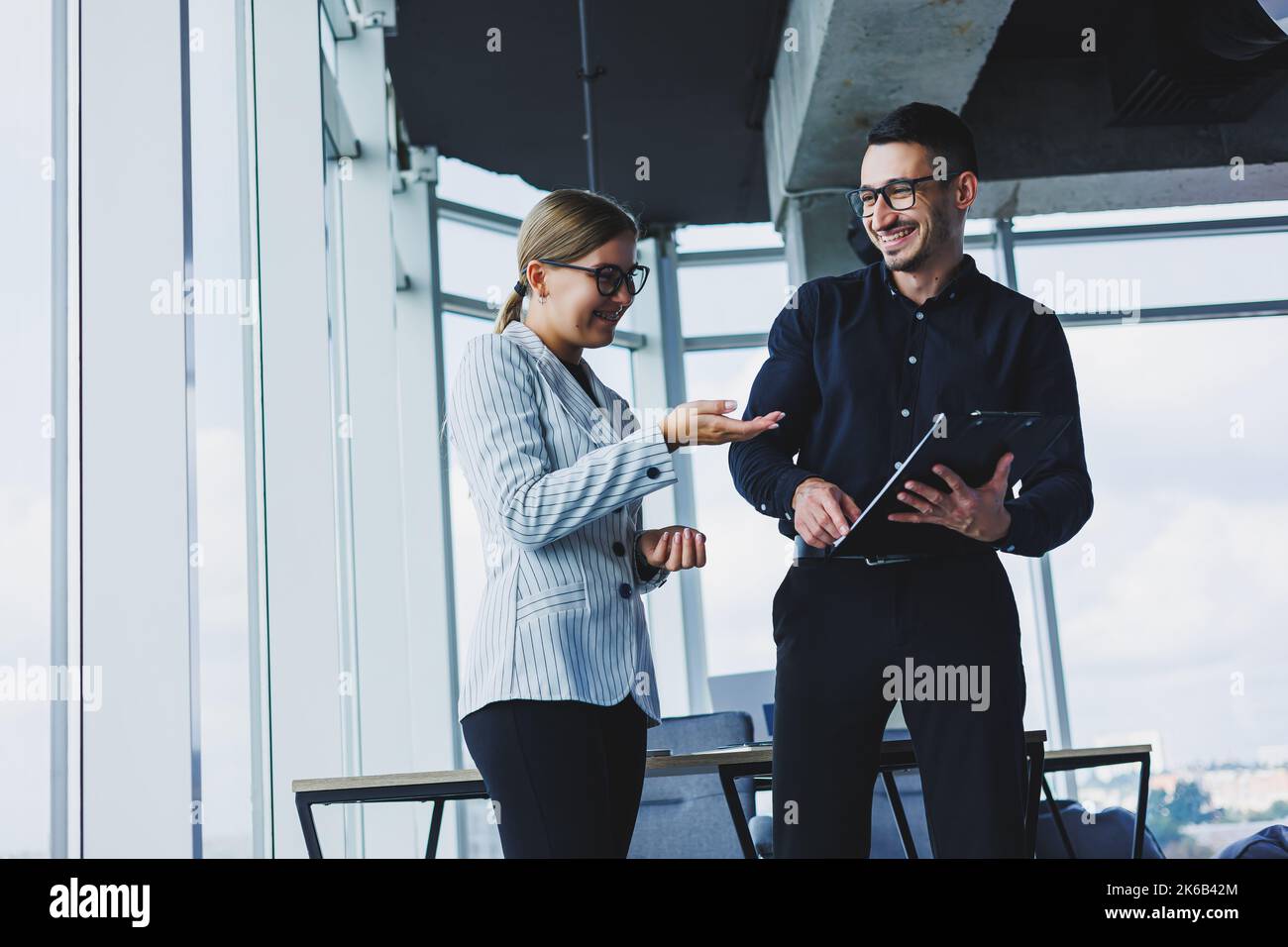 Positive businesswoman standing with Caucasian male colleague talking ...