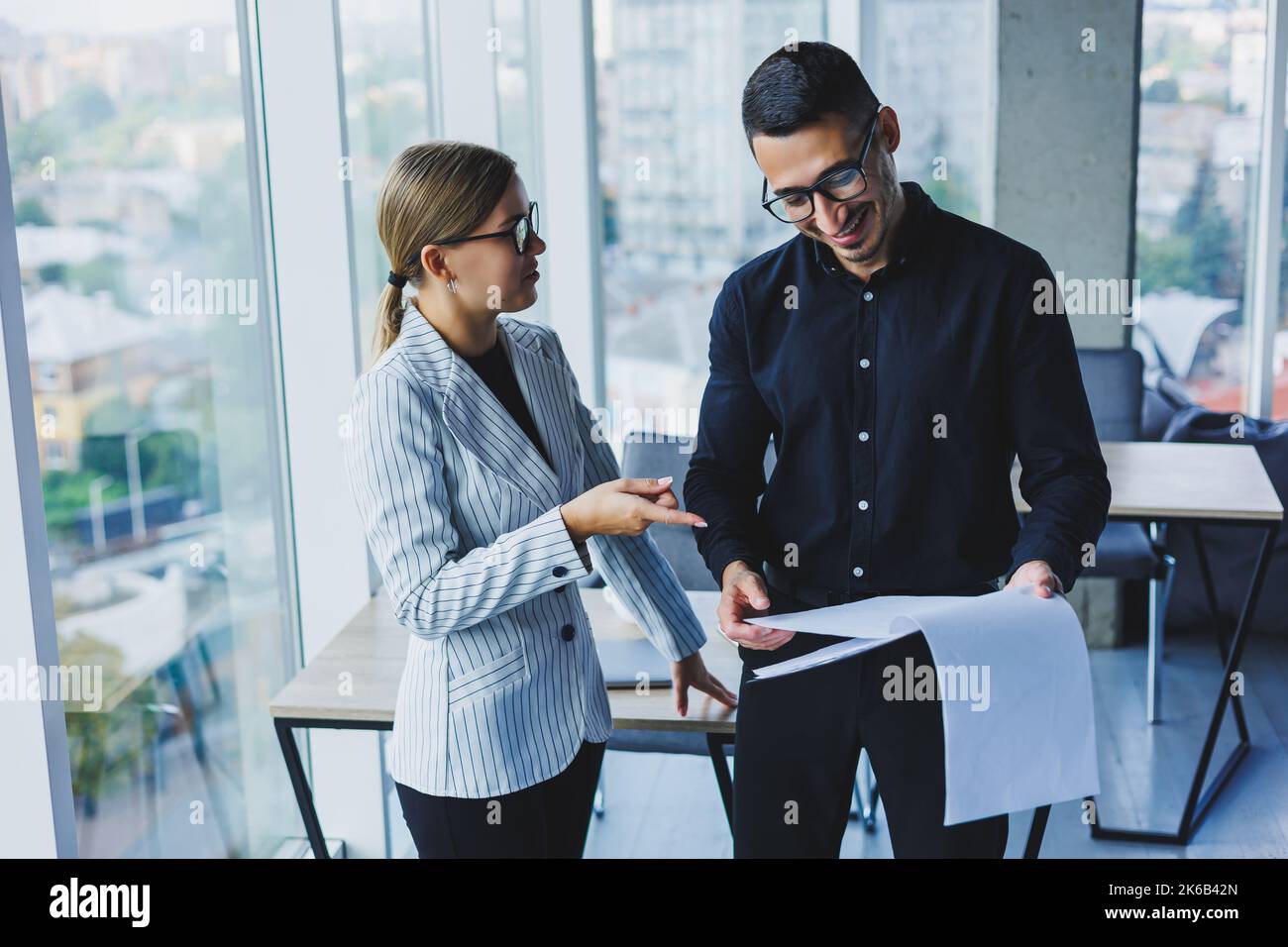 Positive businesswoman standing with Caucasian male colleague talking ...