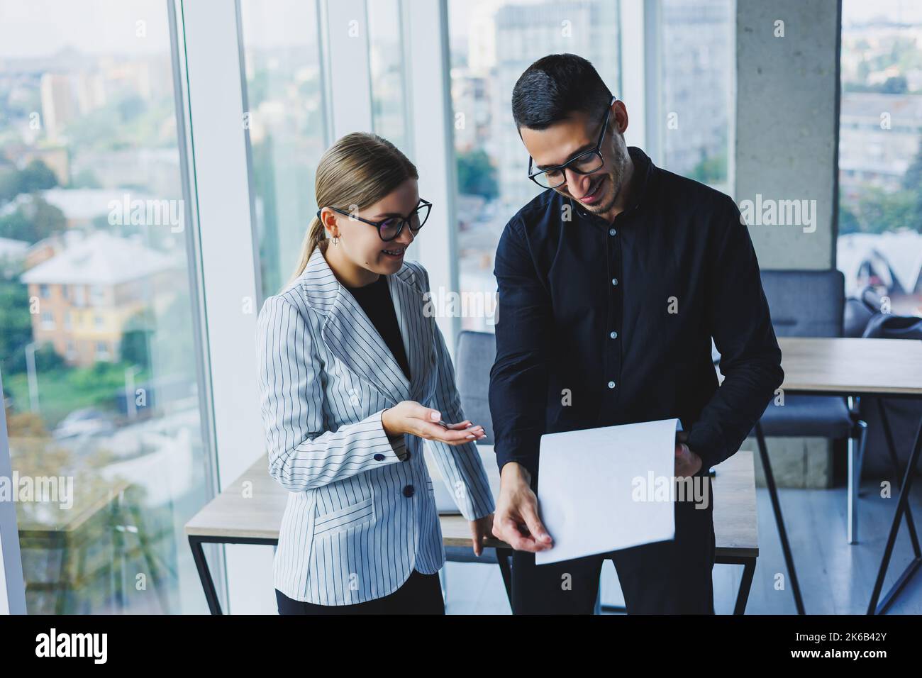 Positive businesswoman standing with Caucasian male colleague talking ...