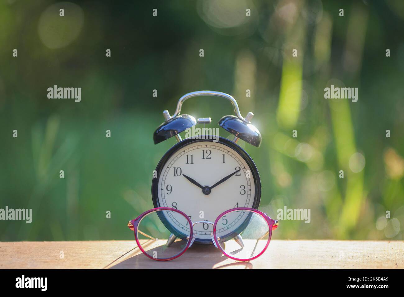 Black alarm clock stacked on wooden bar with purple glasses green ...