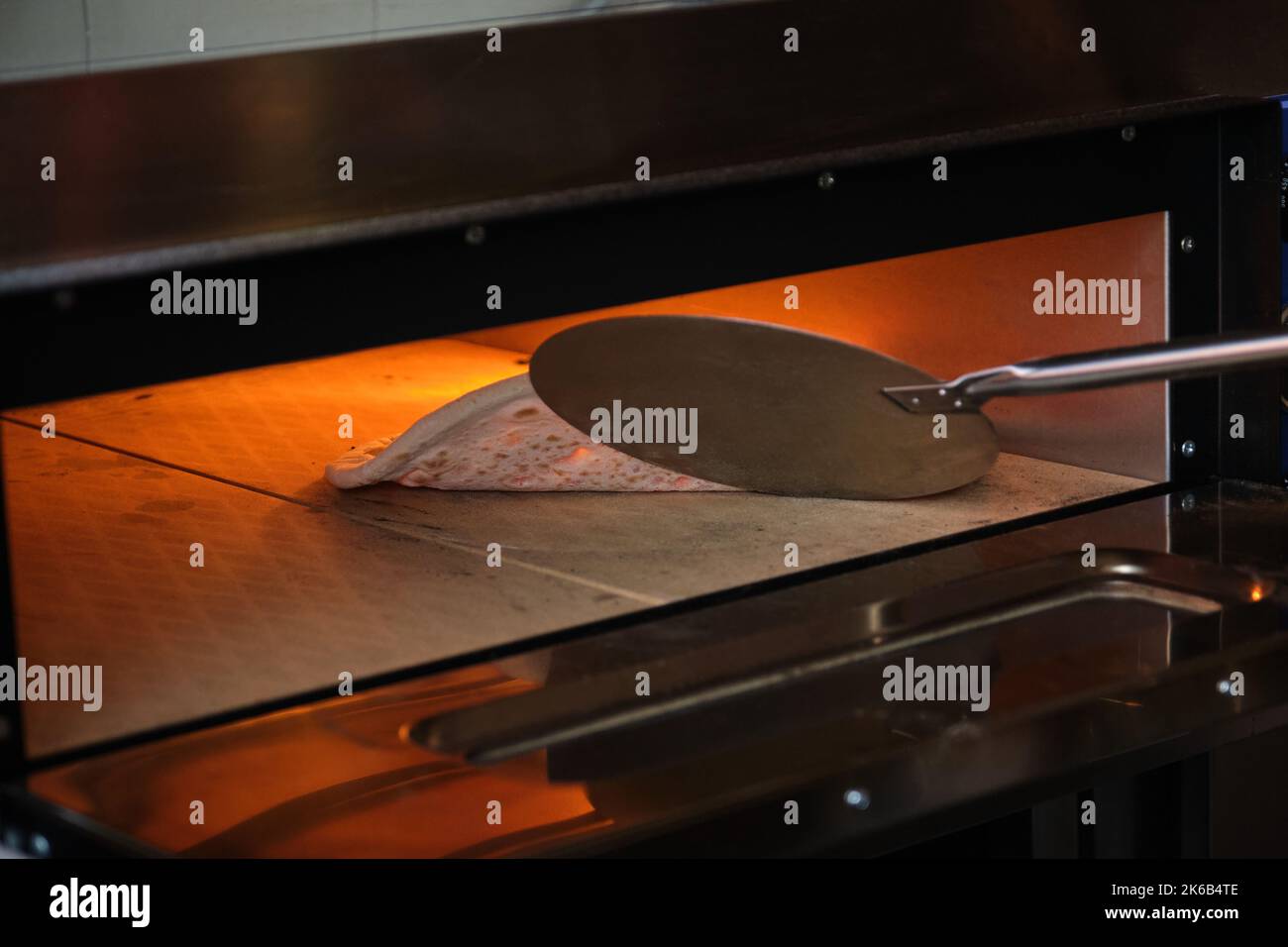 Checking if the pizza is cooked into the oven in a restaurant kitchen ...