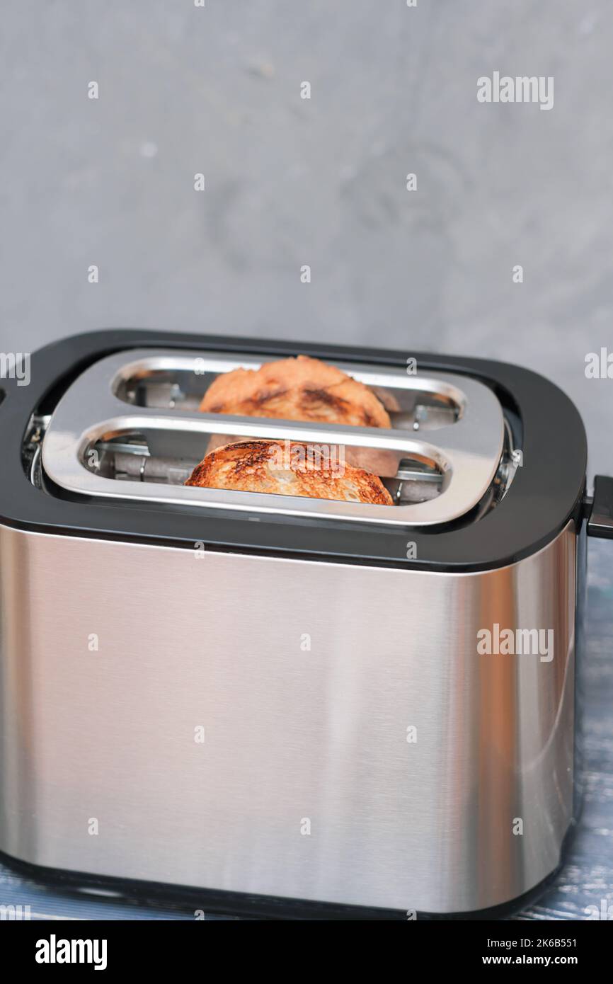 Two roasted crusty pieces of bread on toaster on grey table. vertical ...
