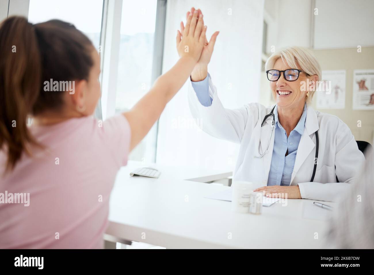 High five for good health. a little girl giving a doctor a high five at ...