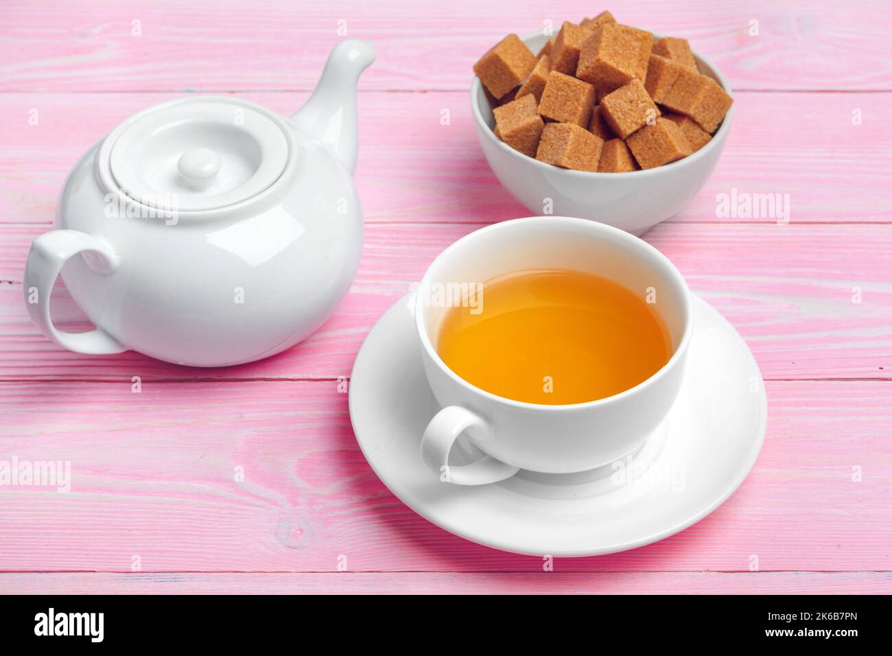 Cup of tea with sugar cubes and flower branches on wooden table close ...