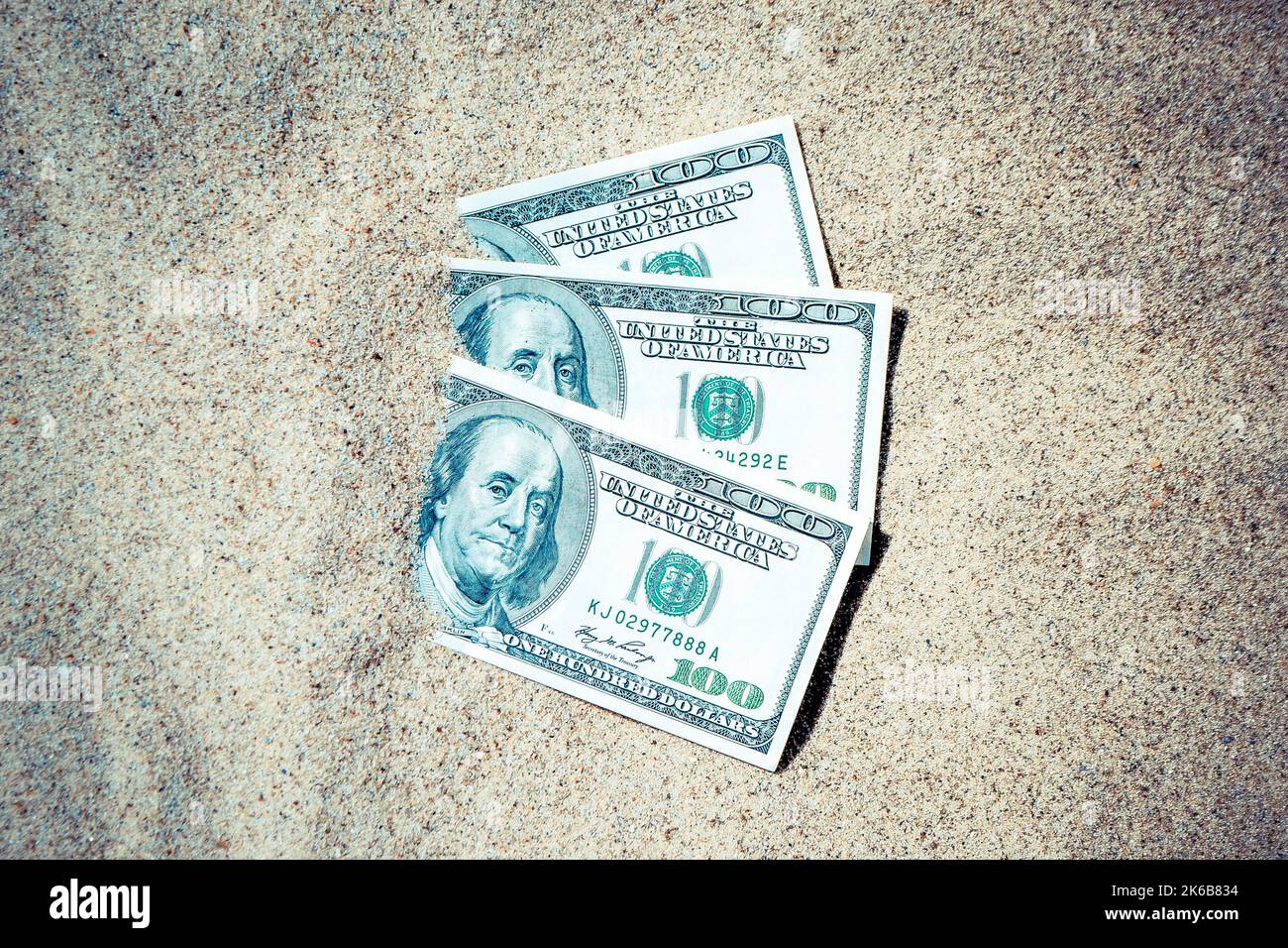 Money dolars half covered with sand lie on beach close-up. Dollar bills ...