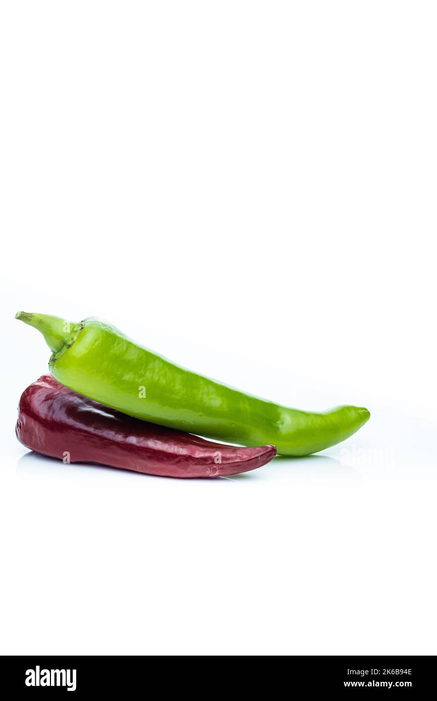 A green chili pepper and a dark red chili pepper isolated on a white ...
