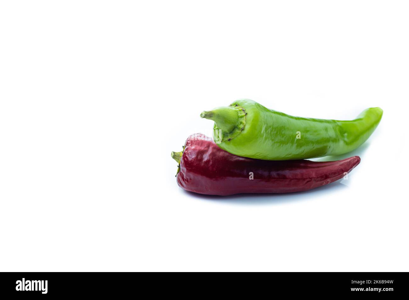 A green chili pepper and a dark red chili pepper isolated on a white ...