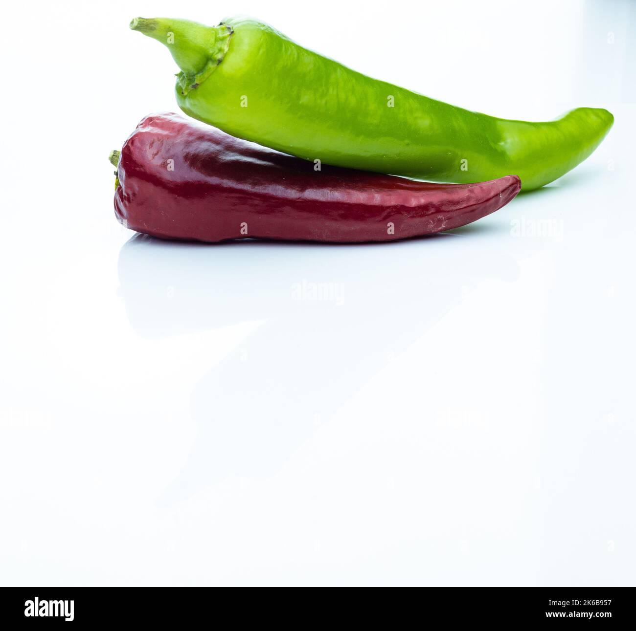 A green chili pepper and a dark red chili pepper isolated on a white ...