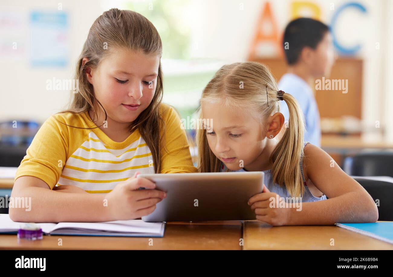 Its her favourite lesson. two girls using a tablet in a classroom Stock ...